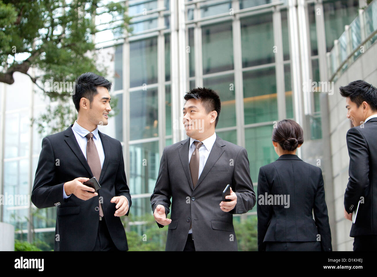 Happy office workers walking and talking with smart phones in hand ...