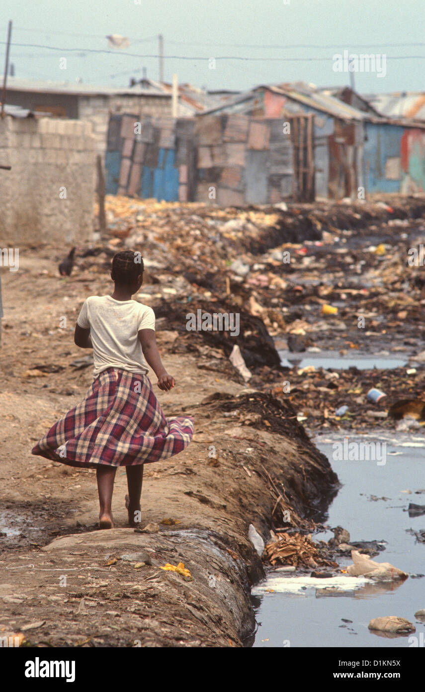 GIRL WALKING BY OPEN SEWAGE IN THE SLUMS OF OF CITE SOLEIL, PORT AU ...