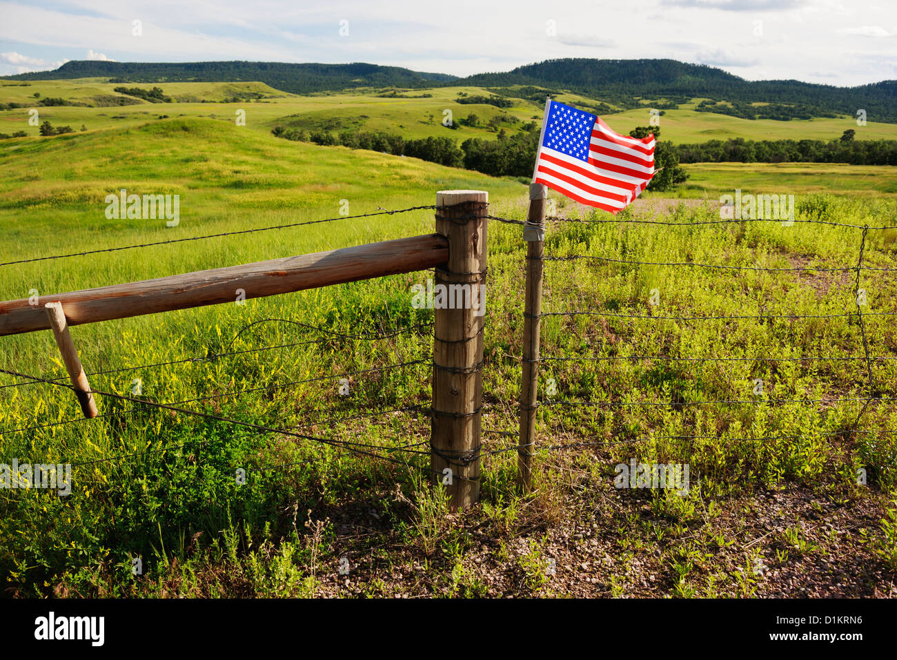 A modest American flag taped to a ranch fence in rural Wyoming snaps in ...