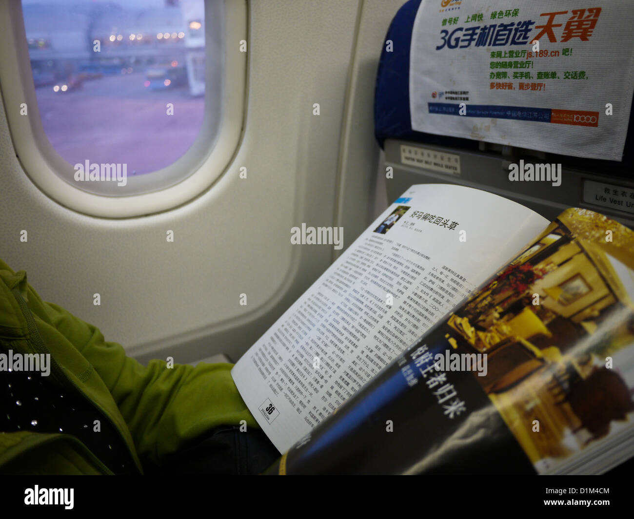 reading magazine inside plane cabinet Stock Photo - Alamy