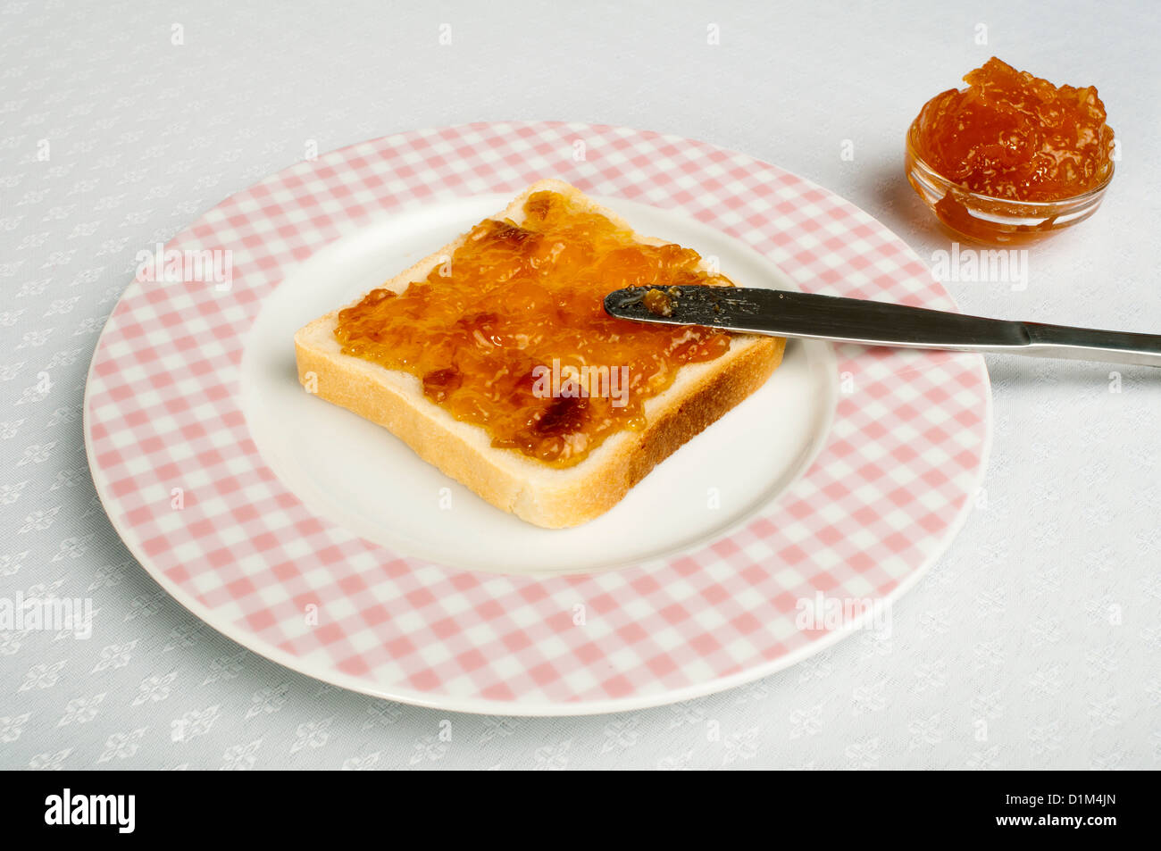 Spread jam on bread with knife. Pink checkered plate Stock Photo - Alamy
