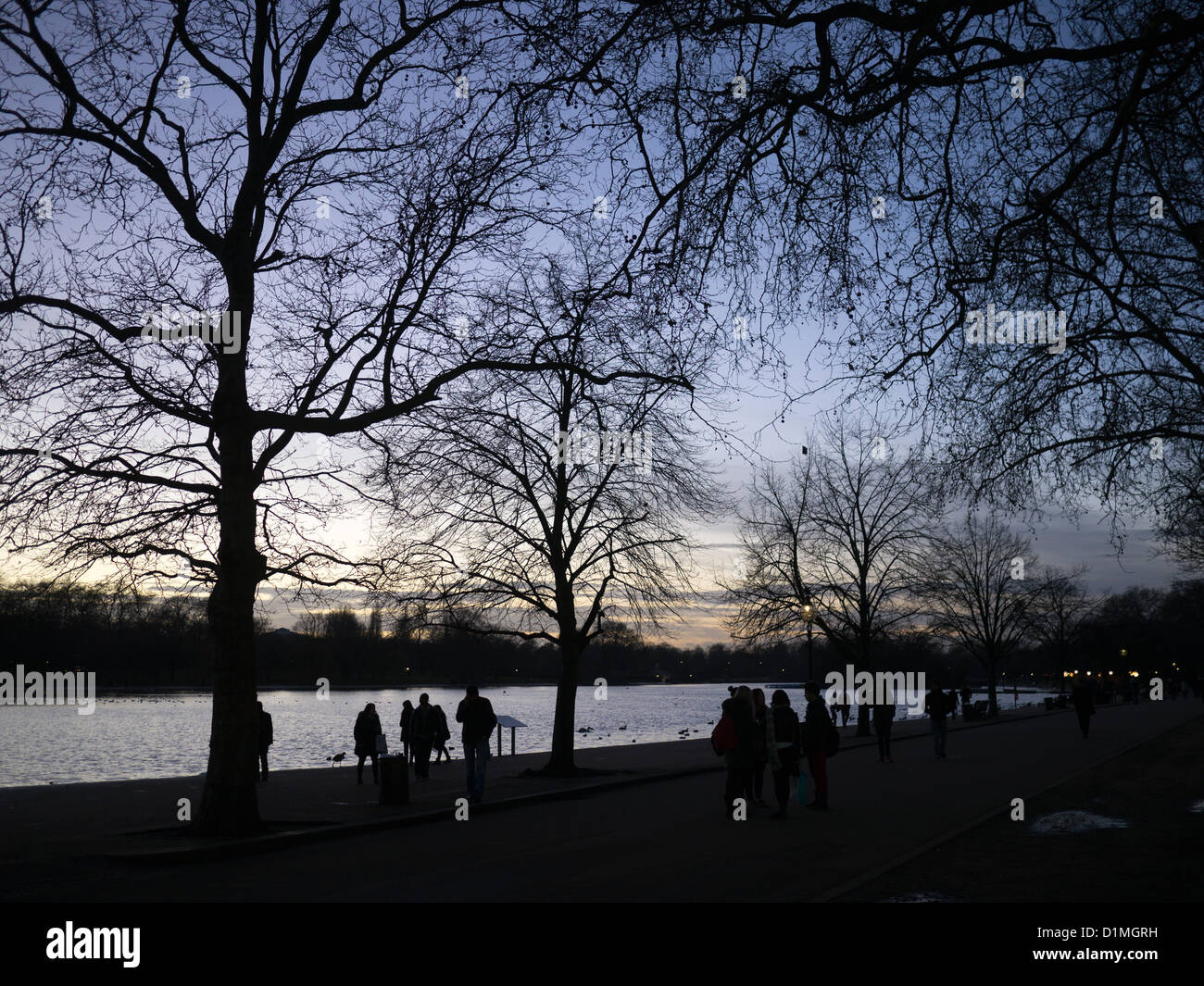 A winter scene with leafless trees and people walking on a cold winters ...