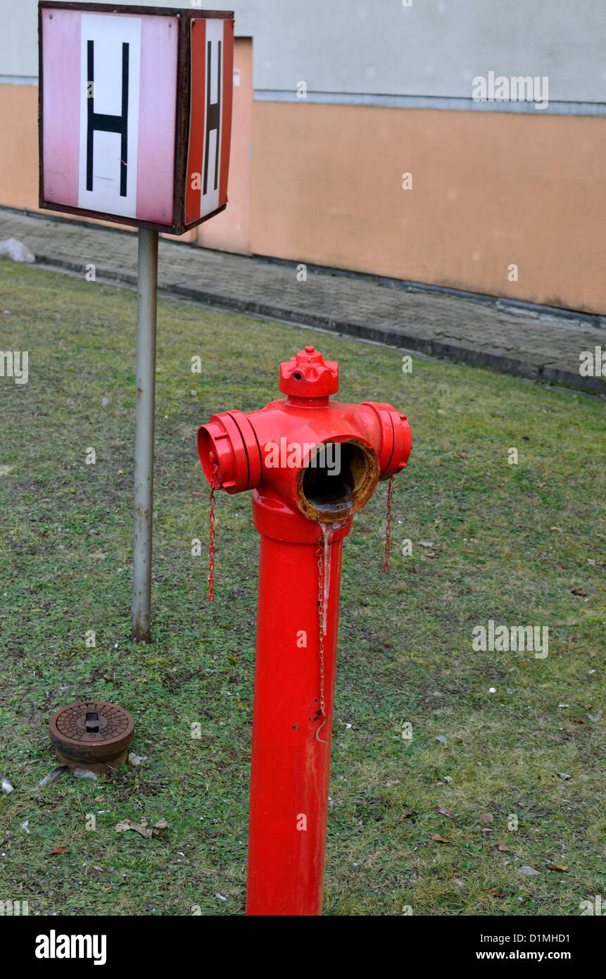 Red fire hydrant in front of wall, on the grass ground Stock Photo - Alamy