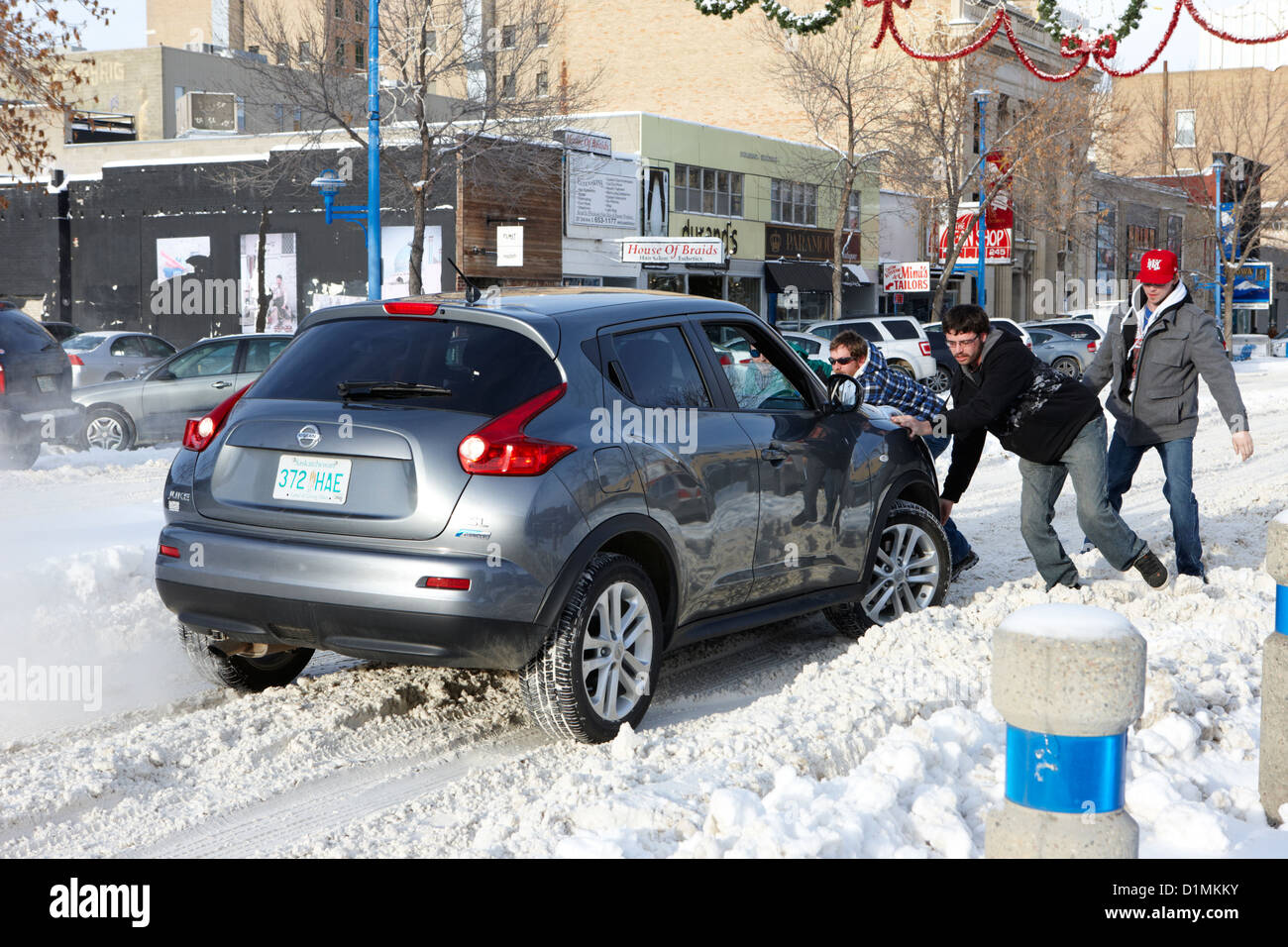 group of men pushing car stuck in deep snow on downtown city street ...