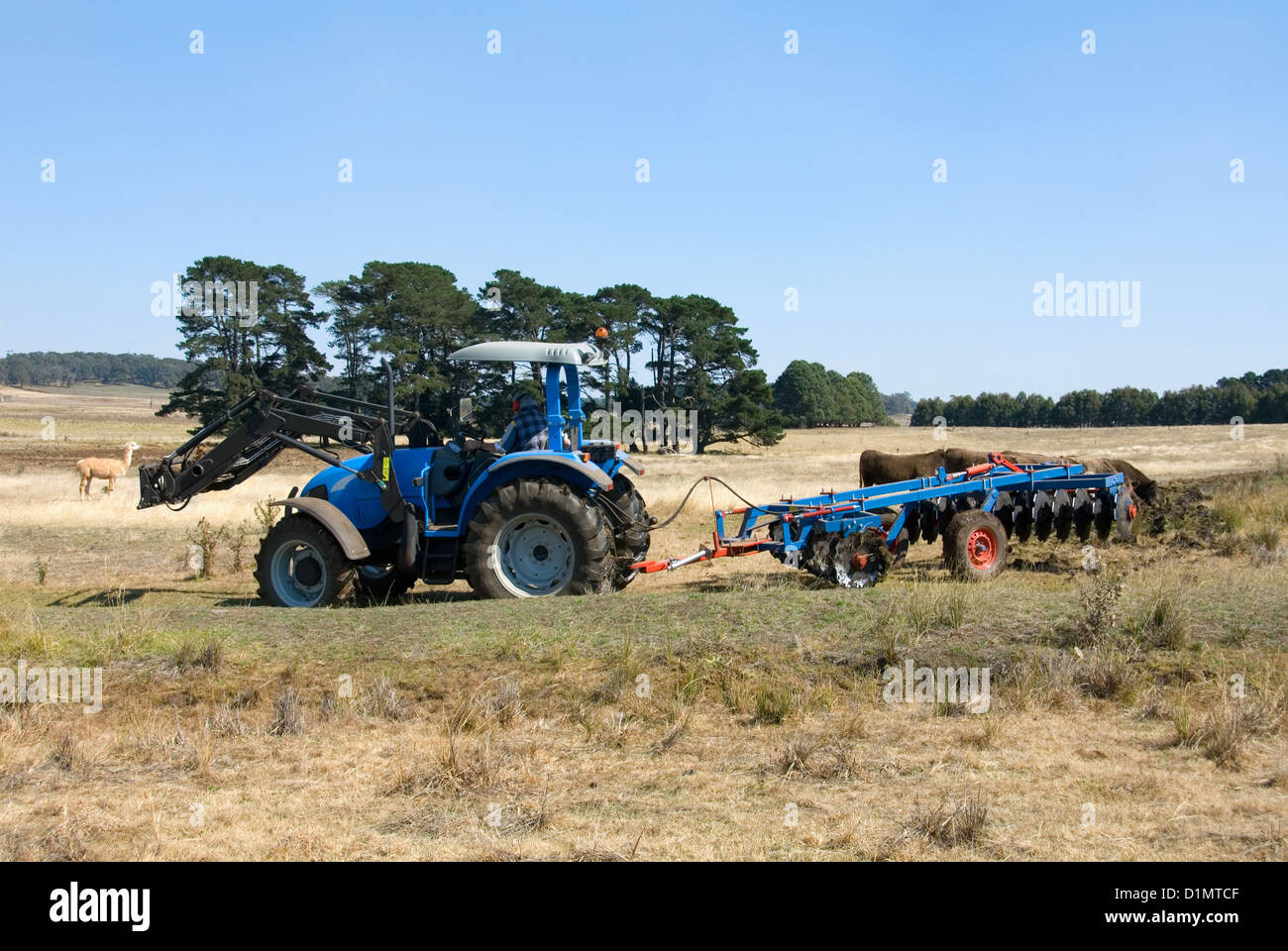 A tractor pulling a plough, in a field Stock Photo - Alamy