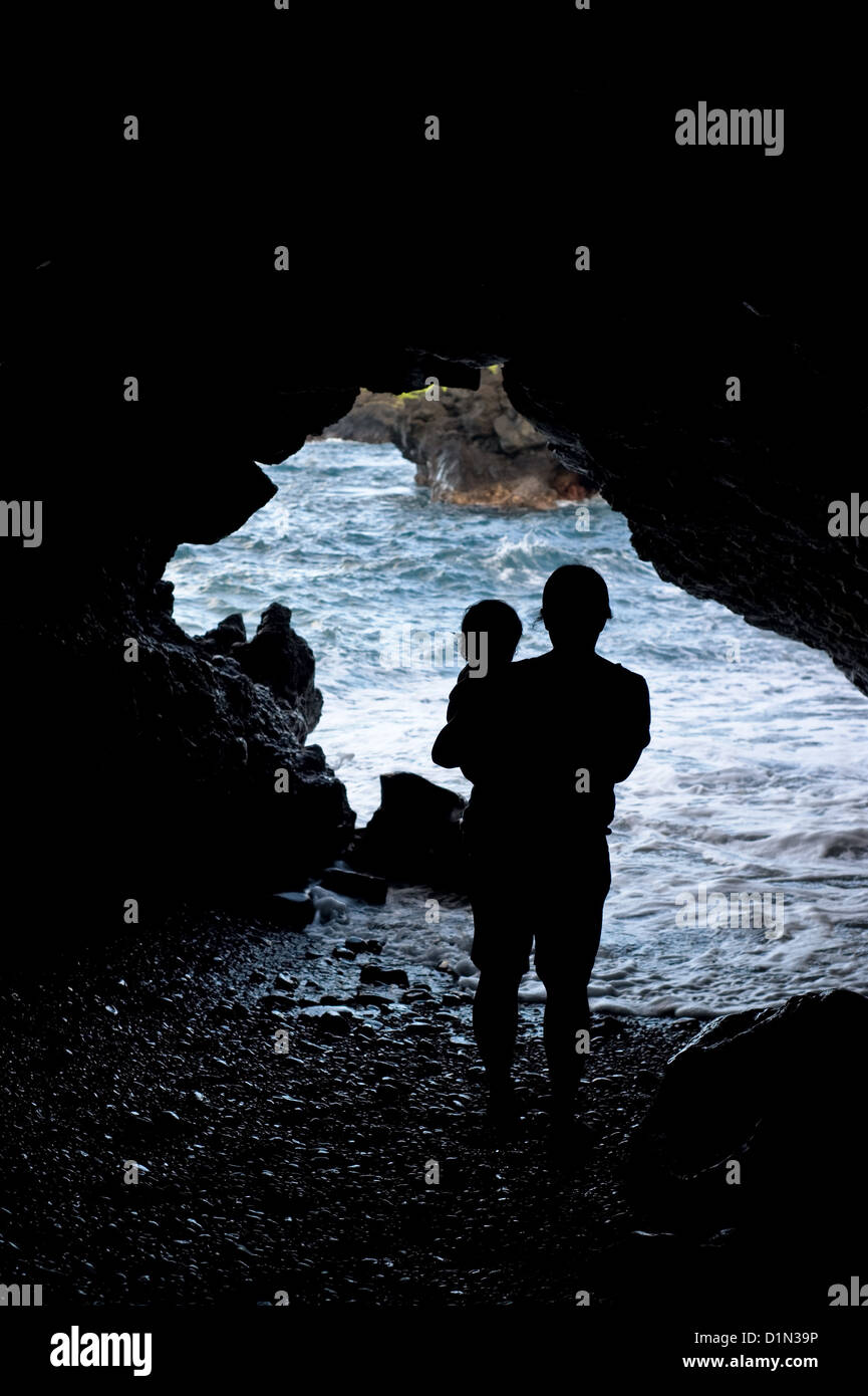 A young mother and her baby admire the crashing waves inside a cave in ...