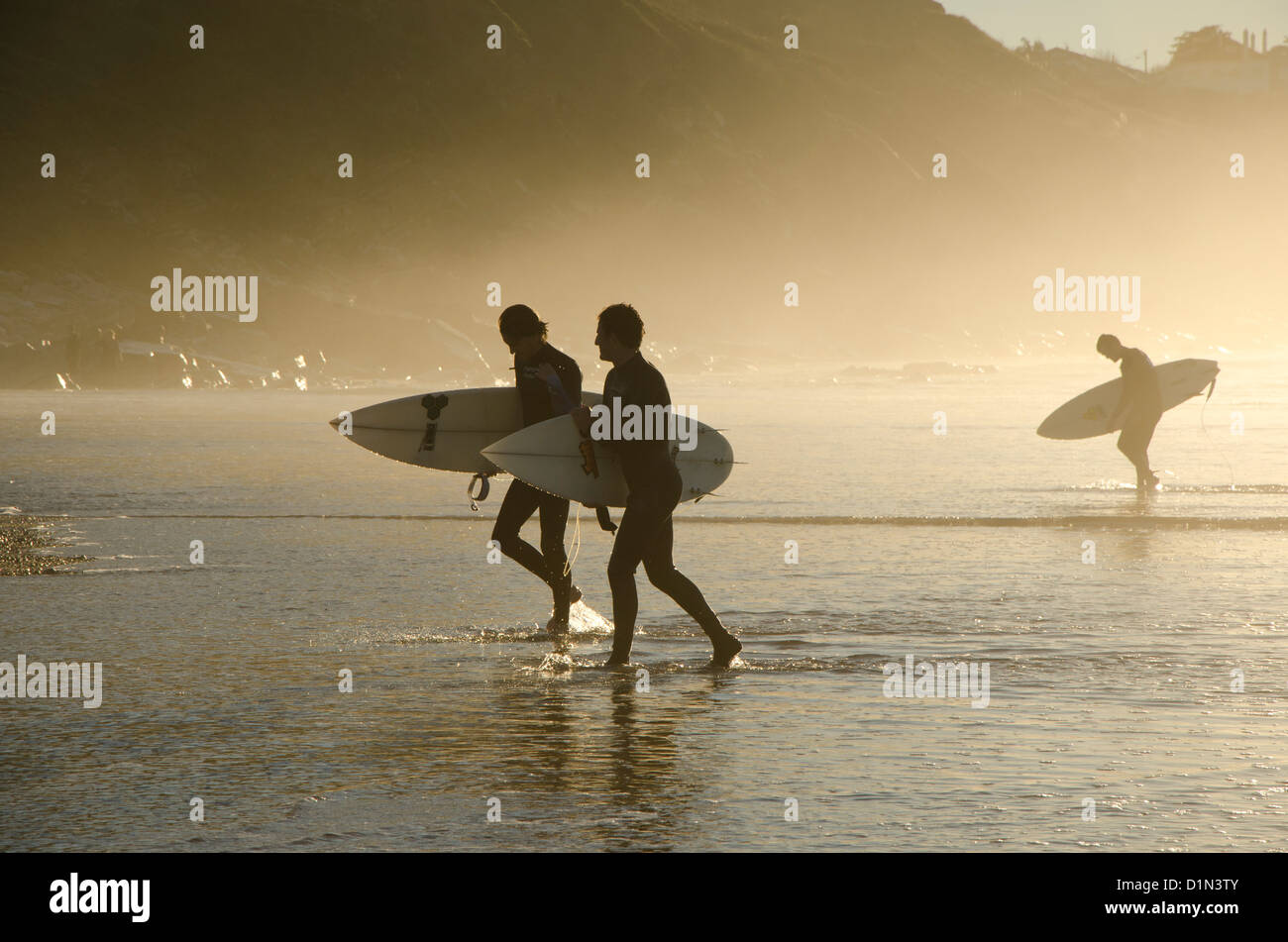 Surfers leaving the waves behind at a beach near Biarritz during sunset ...