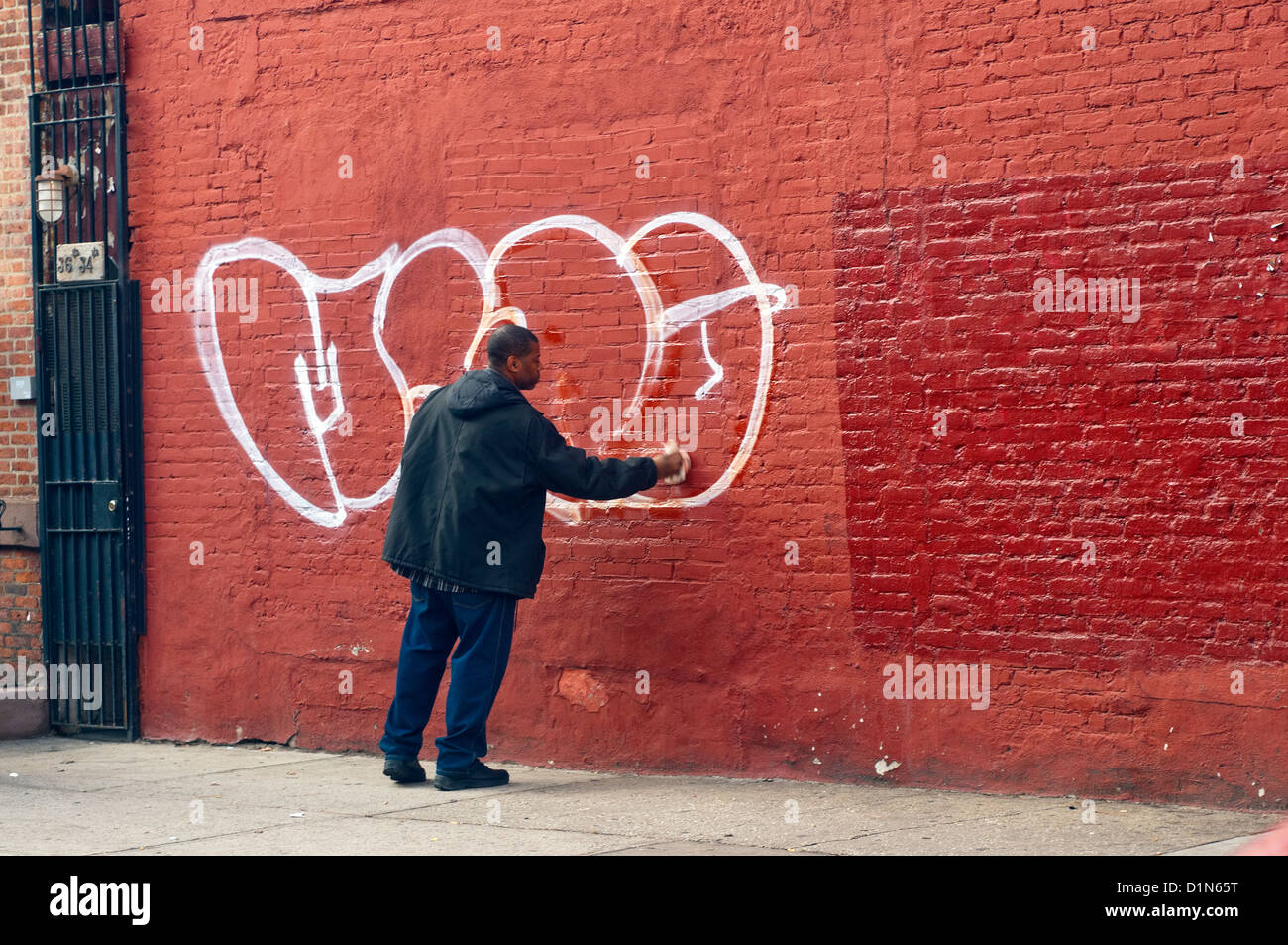 New York, NY - 23 December 2012 Man cleaning graffiti off a red brick ...
