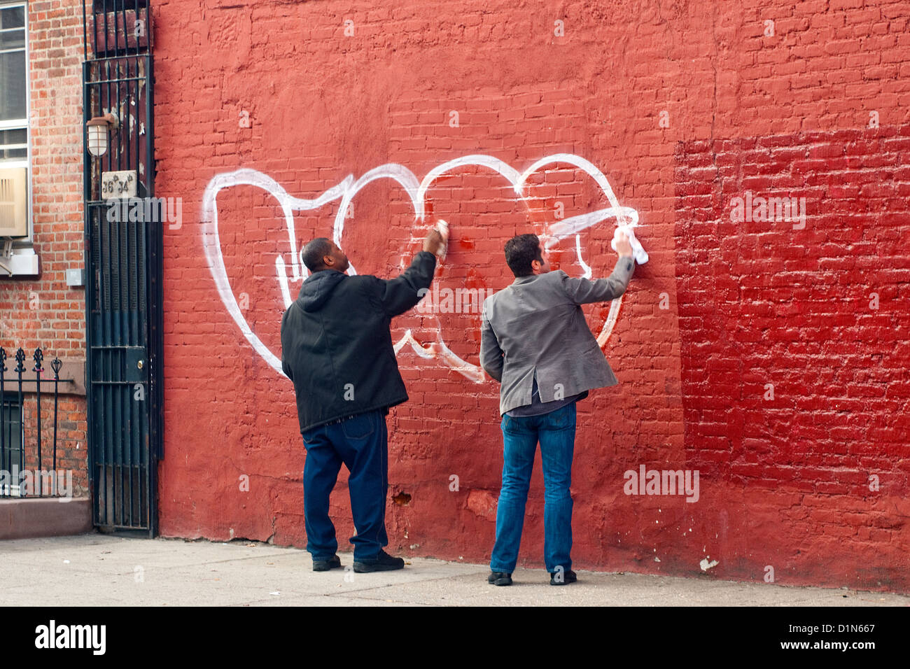 New York, NY - 23 December 2012 Two men clean graffiti on a red brick ...