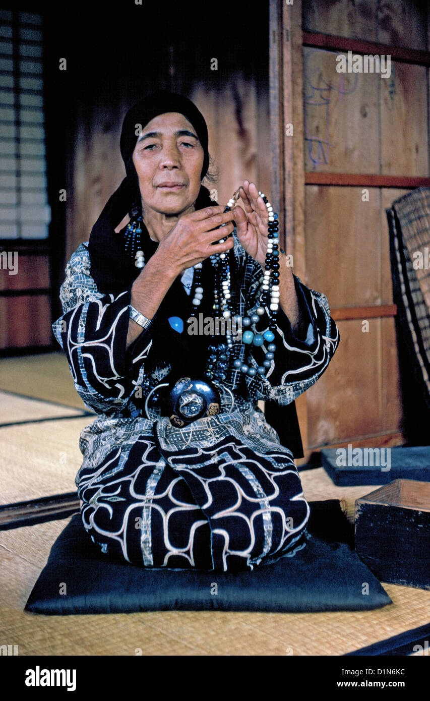 An elderly Ainu woman in traditional dress shows off her prized ...
