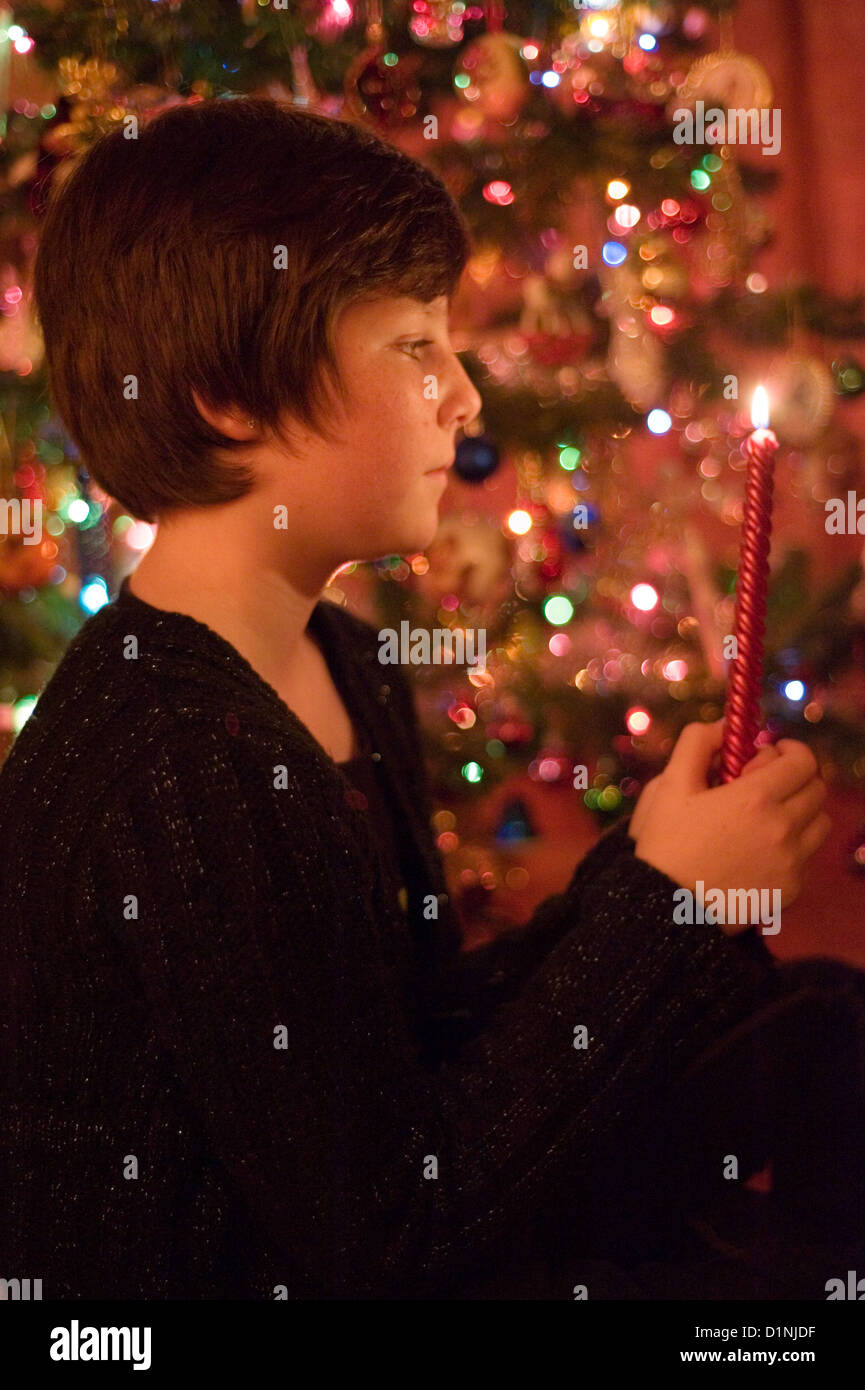 young girl lit by the candle she is holding with fairy lights on ...