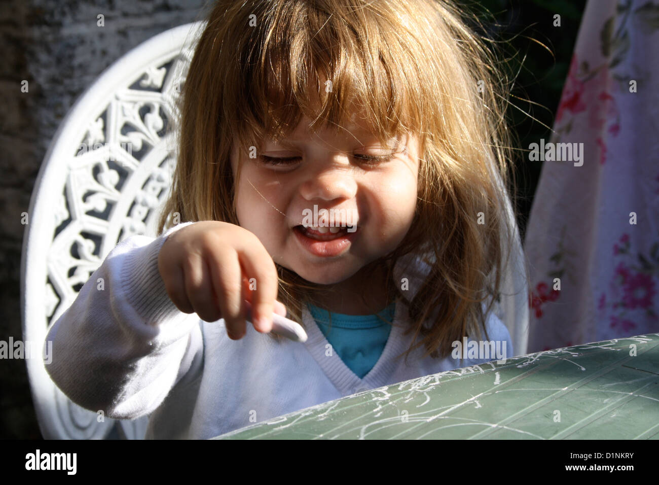 A child draws with chalk outside Stock Photo - Alamy