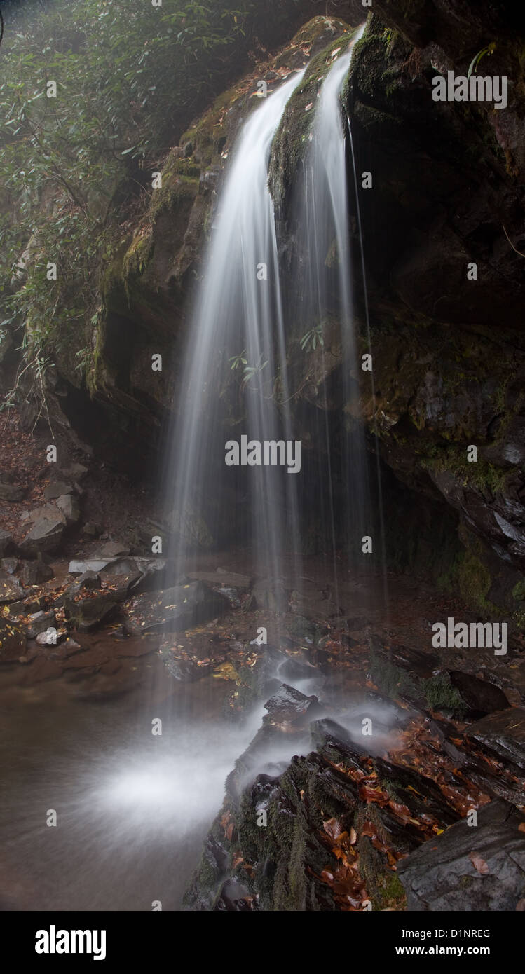 Mountain waterfall with morning mist drifting down from above and a ...