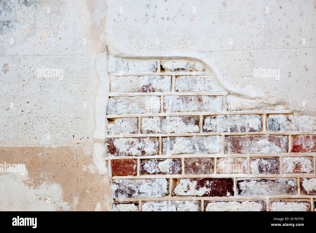 Brick wall with plaster on top, and the plaster is cracked and breaking ...