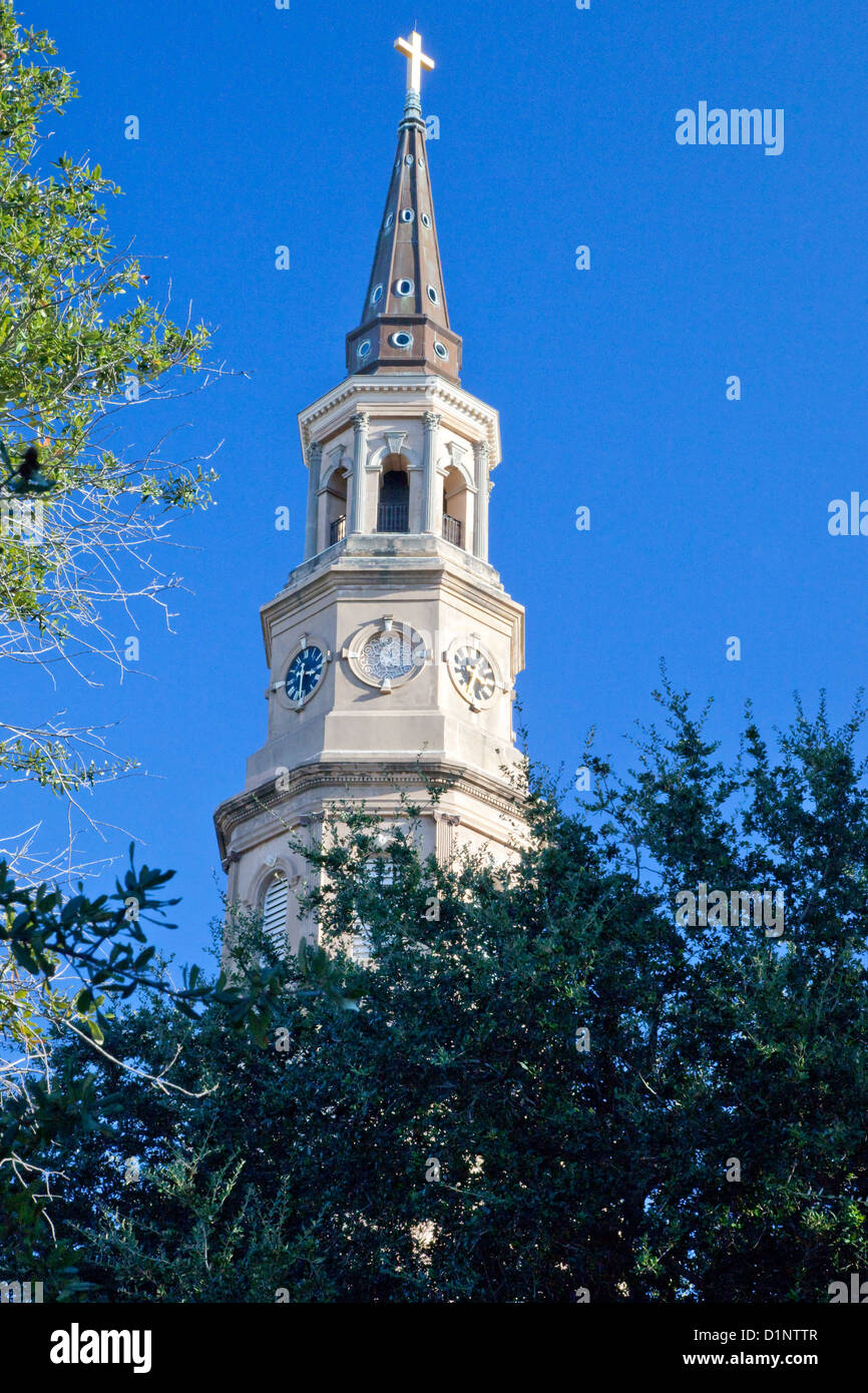 Christian Church steeple against a blue sky with trees in the ...