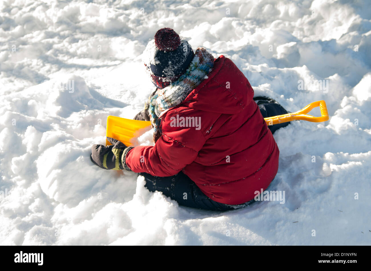 Vietnamese boy playing outdoor on a pile of snow on a sunny winter day ...