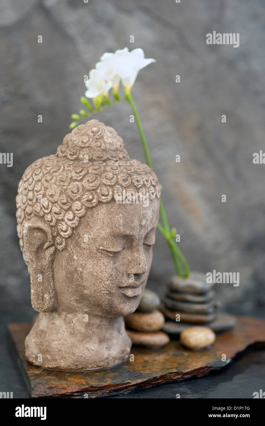Stone Buddha head sculpture, stones, and flower in watery element Stock ...