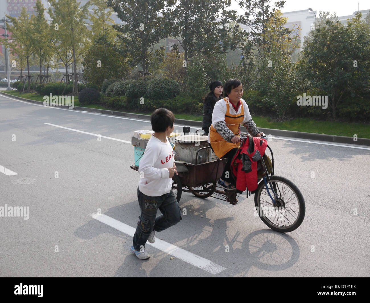 chinese children running mother riding bike Stock Photo - Alamy