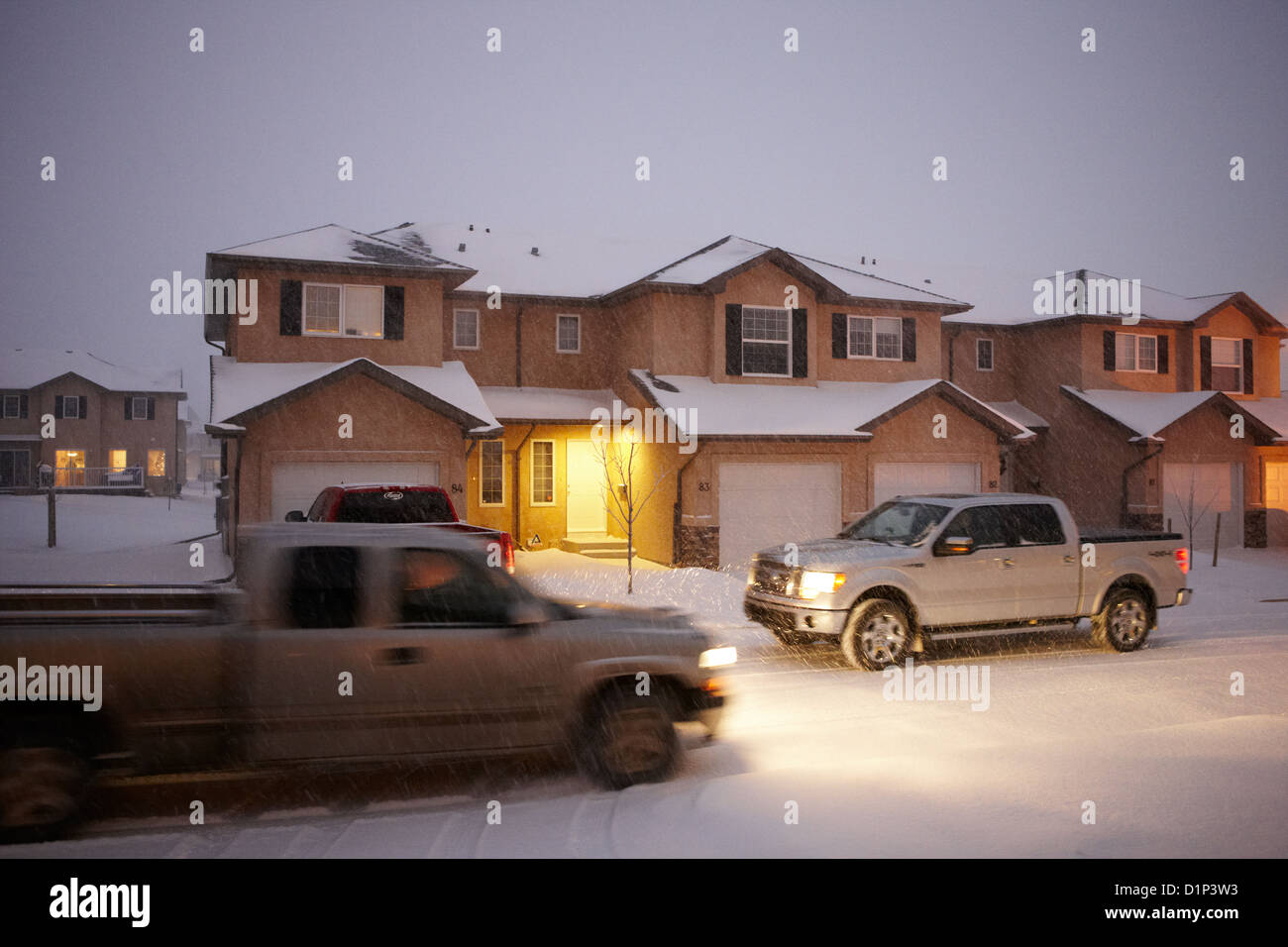 trucks driving through street with snow falling in residential ...