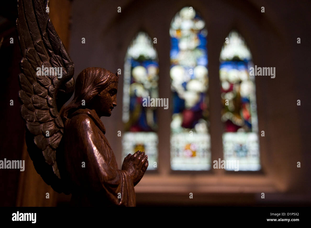 An angel in prayer in front of a stained glass window in Christ Church ...