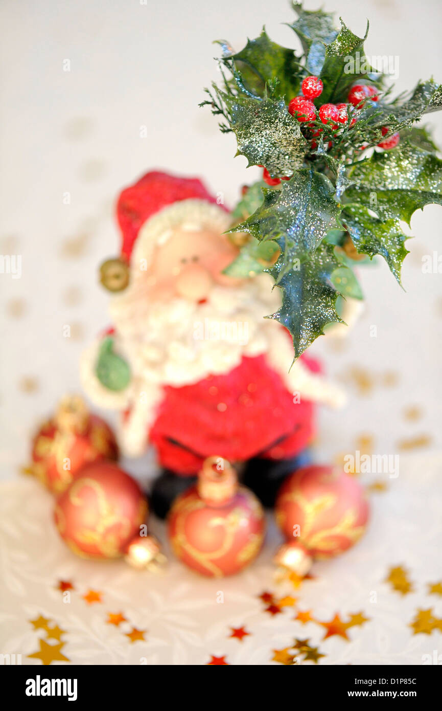 Small Father Christmas figure with red coat and hat holding a branch of ...