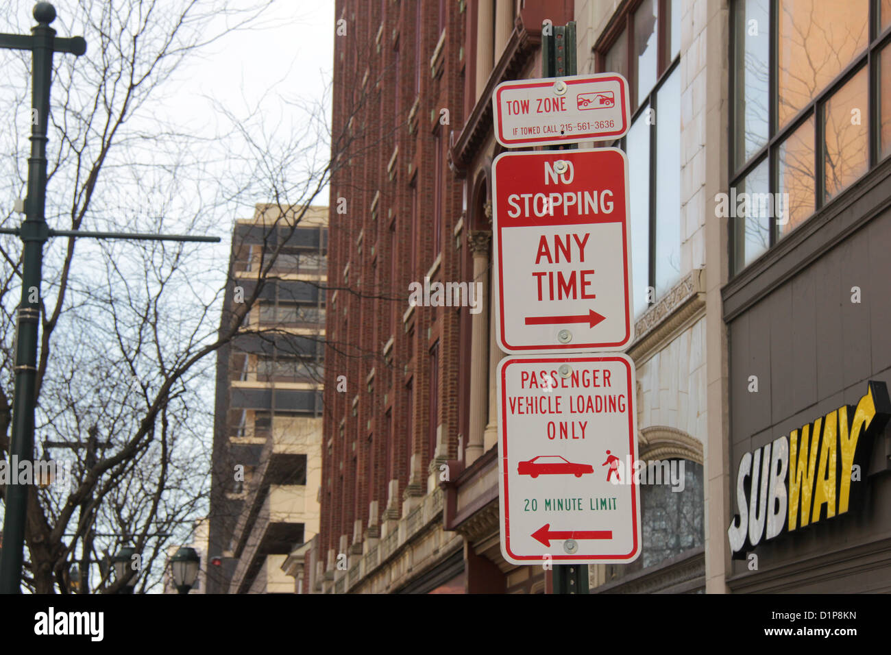 Several traffic signs in a post outside a Subway restaurant in ...