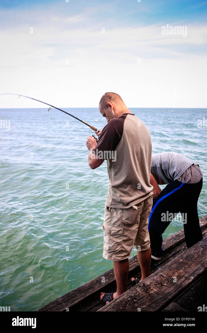 Fisherman pulls on his rod trying to reel in a big fish from the Gulf ...