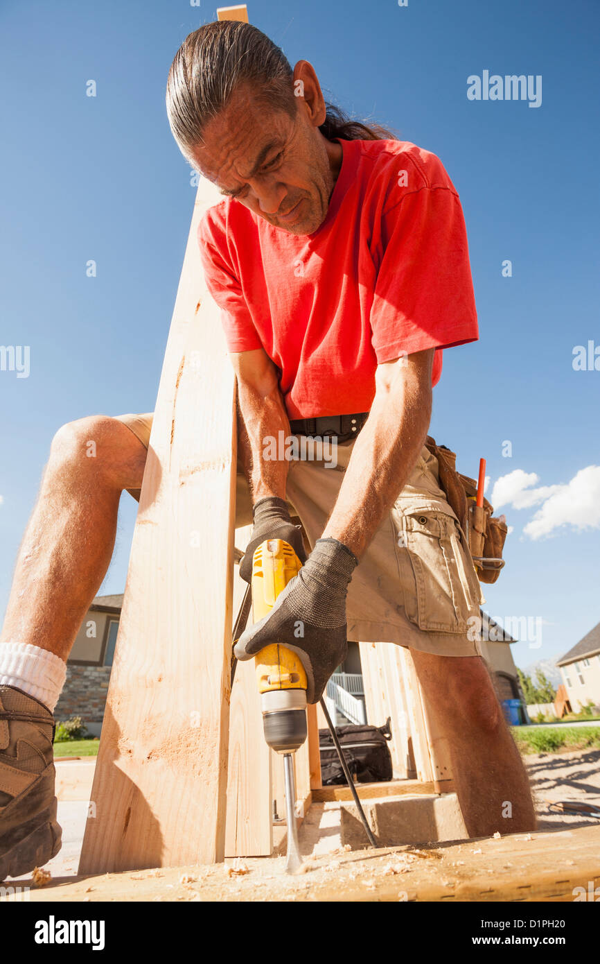 Hispanic man using drill on construction site Stock Photo - Alamy