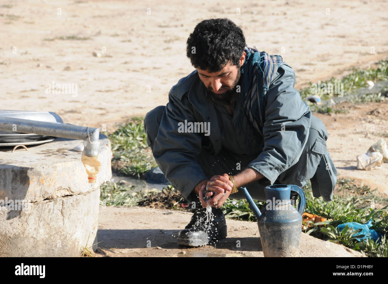 An Afghan National Police officer washing his hands at a well in Bala ...