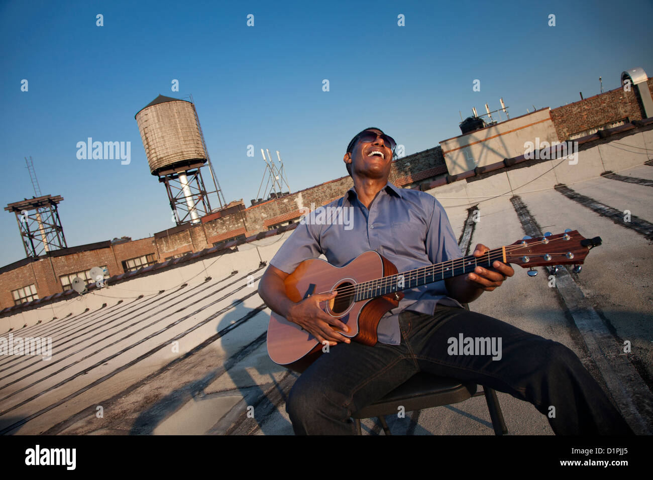 Black man playing guitar on rooftop Stock Photo - Alamy