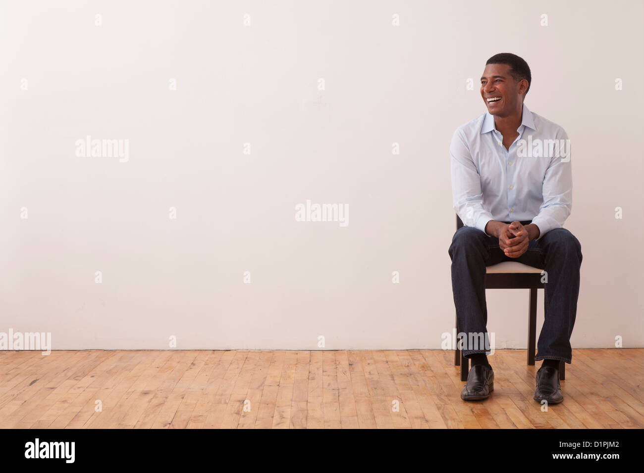 Black man sitting in chair Stock Photo - Alamy