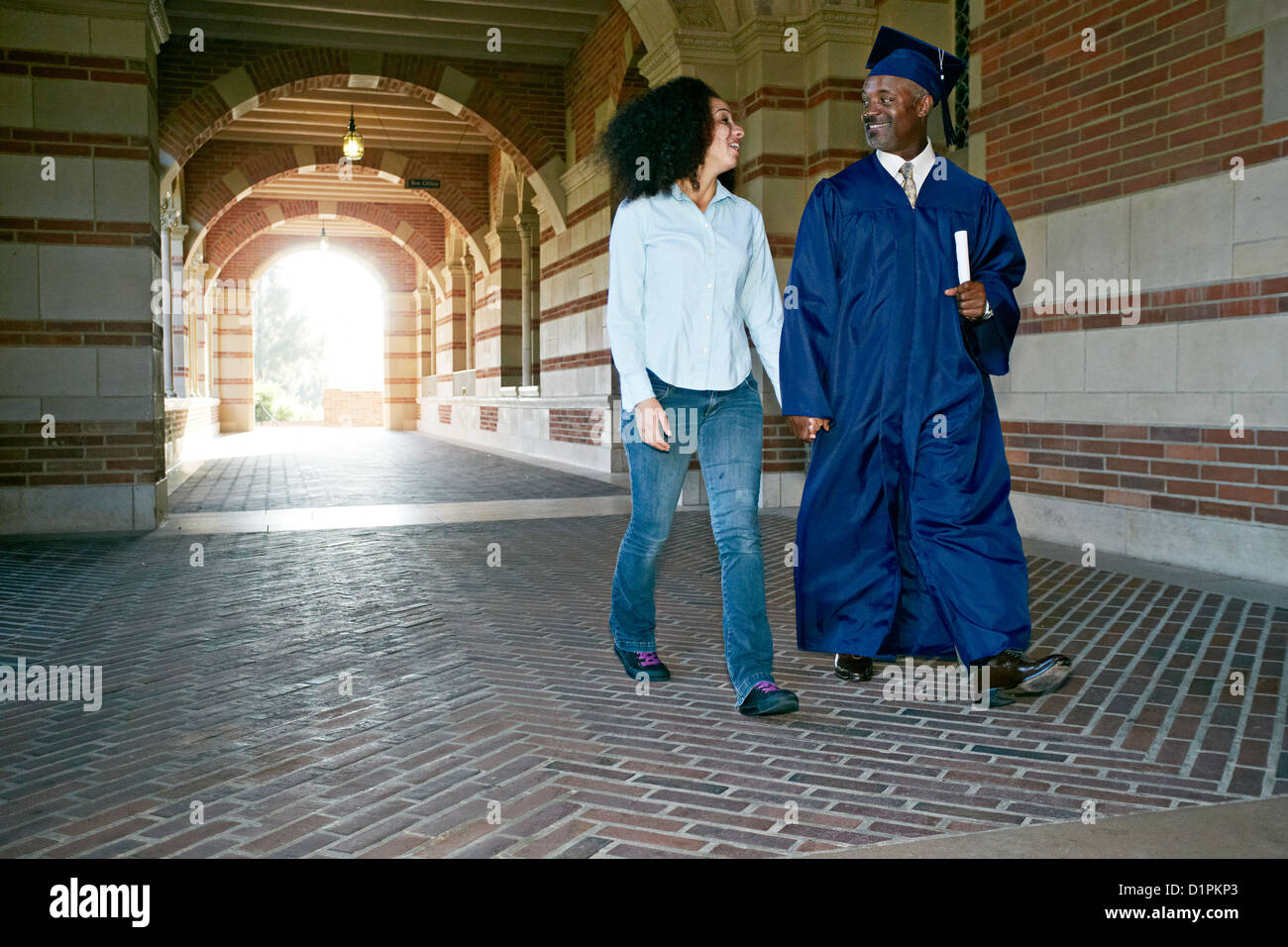 Daughter walking with father in graduation cap and gown Stock Photo - Alamy