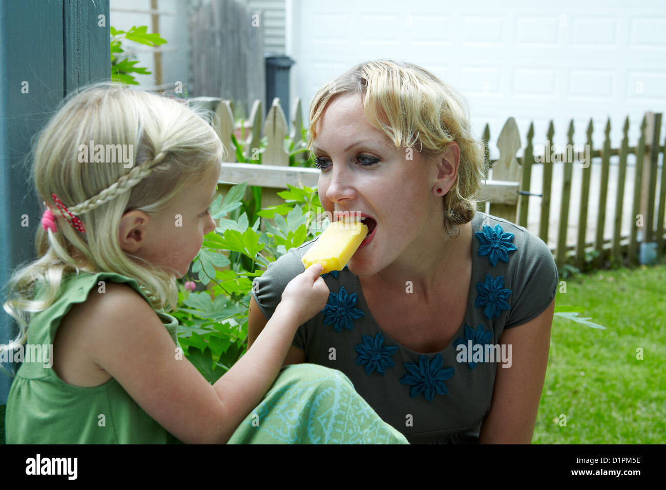 Mother and daughter sharing popsicle Stock Photo - Alamy