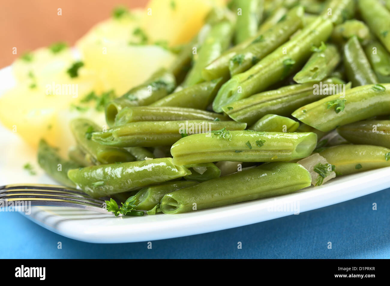 Cooked green beans with onion and parsley with cooked potato in the ...