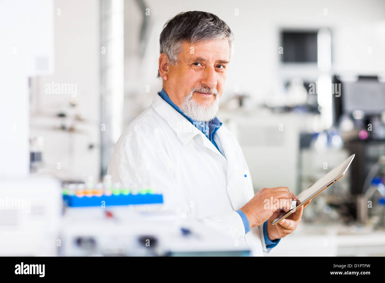 Senior doctor using his tablet computer at work (color toned image ...