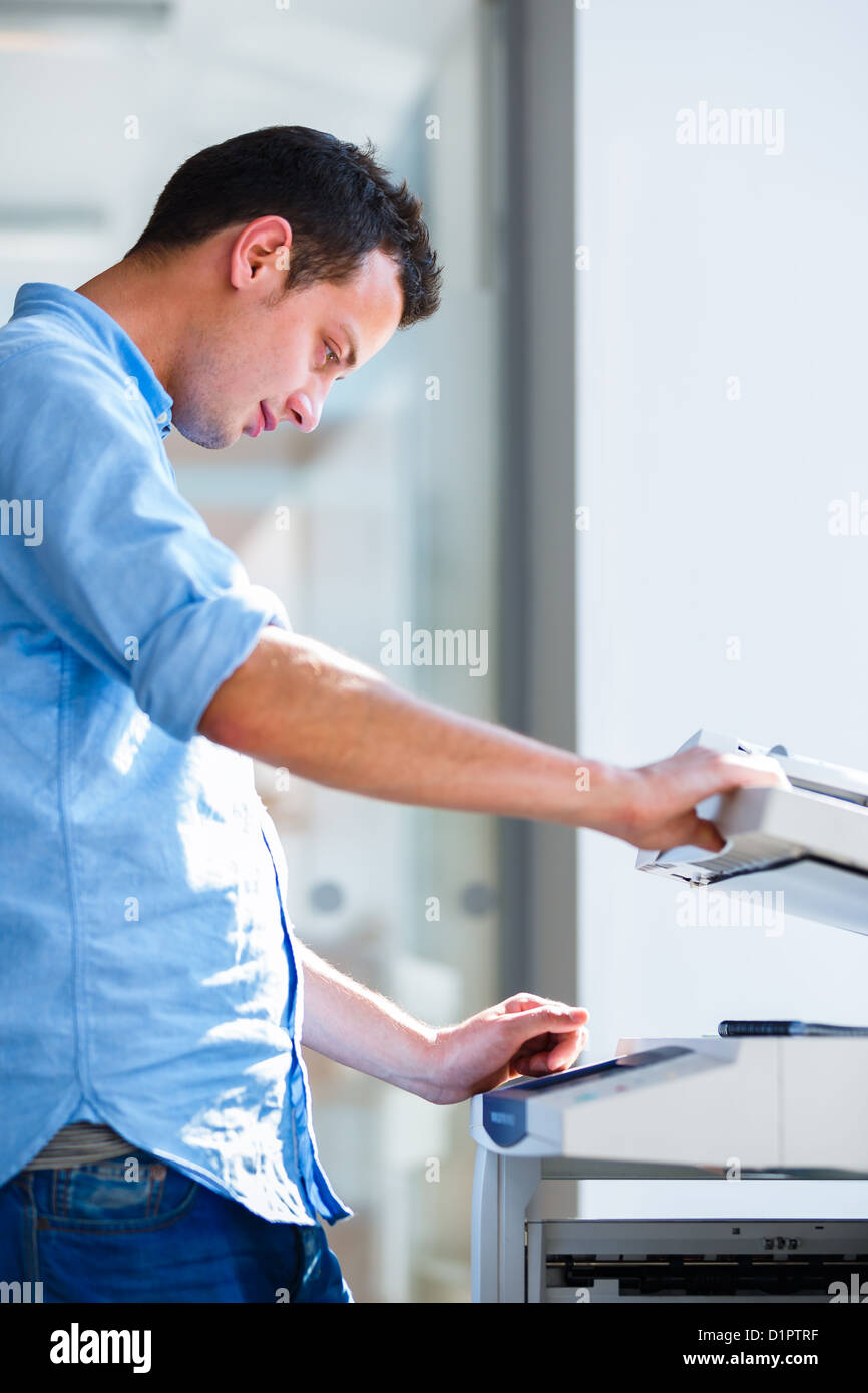 Handsome young man using a copy machine (shallow DOF; color toned image ...
