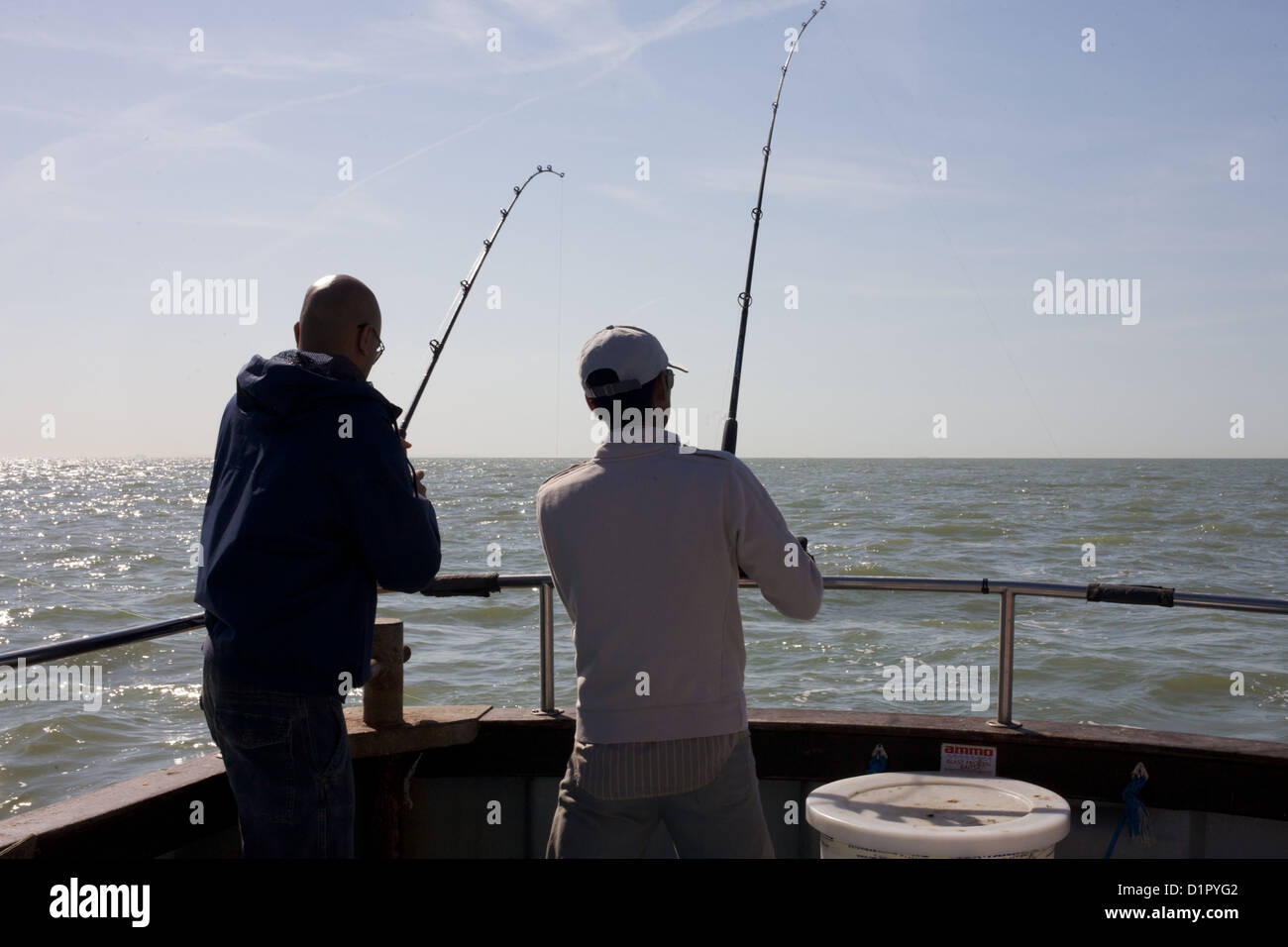 two men fishing for sea bass in the English channel, with rods, off the ...