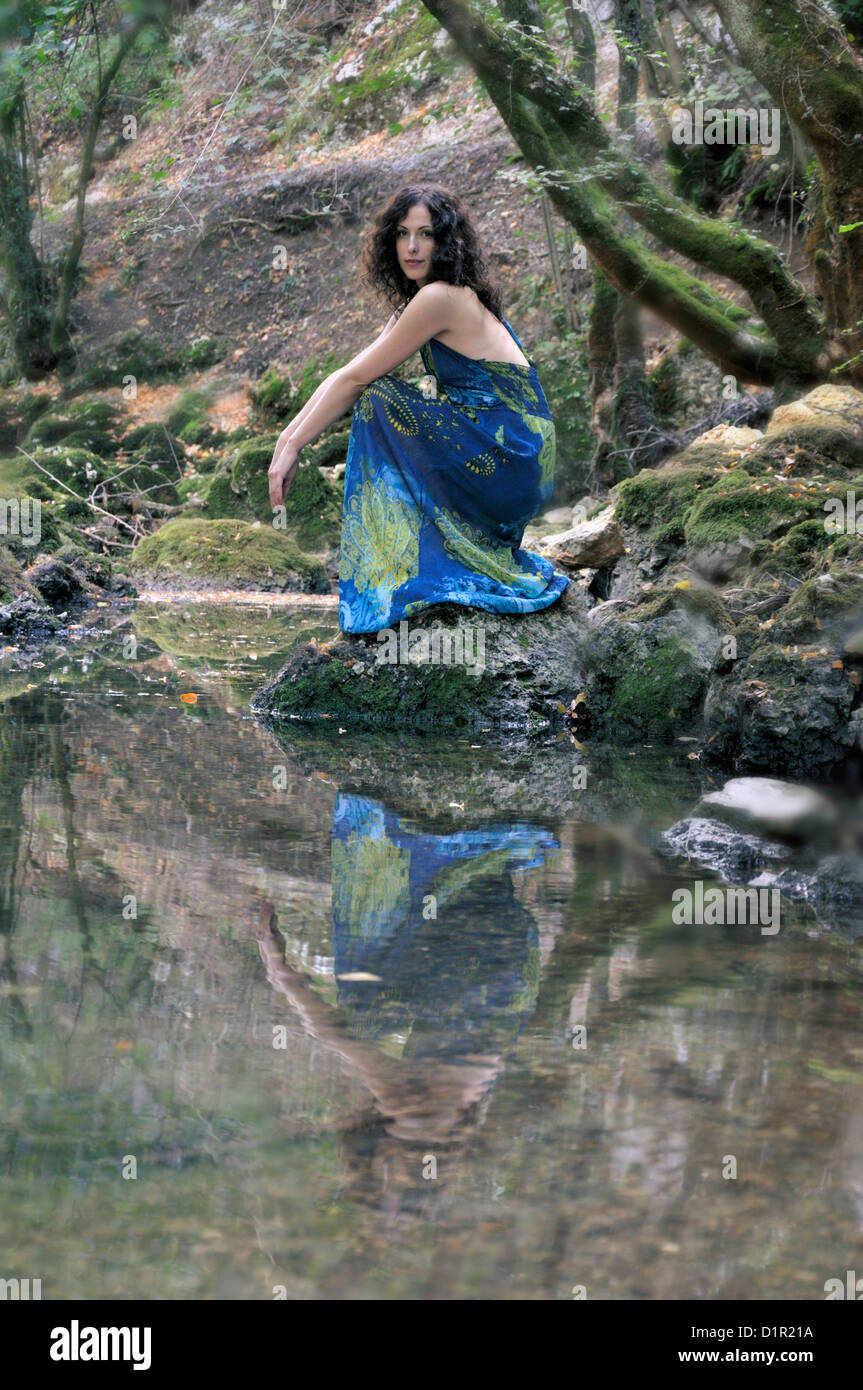 Young beautiful woman kneeling by river Stock Photo - Alamy