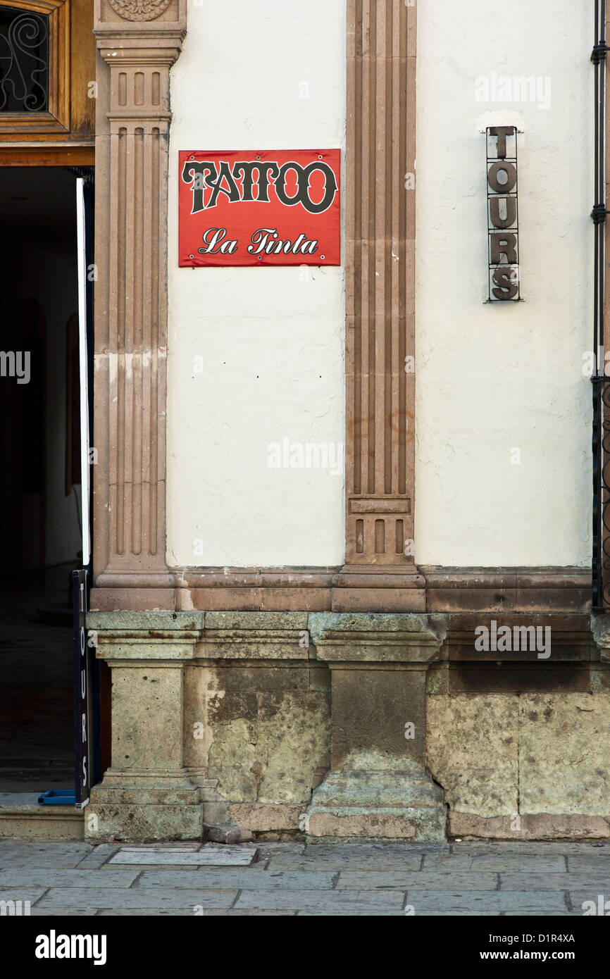 signs advertising tours & a Tattoo parlor on the facade of Spanish ...
