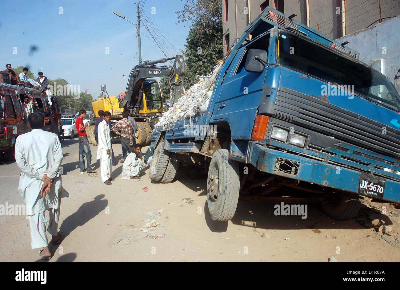 Heavy machinery uplifting an overloaded truck that slipped down in a ...