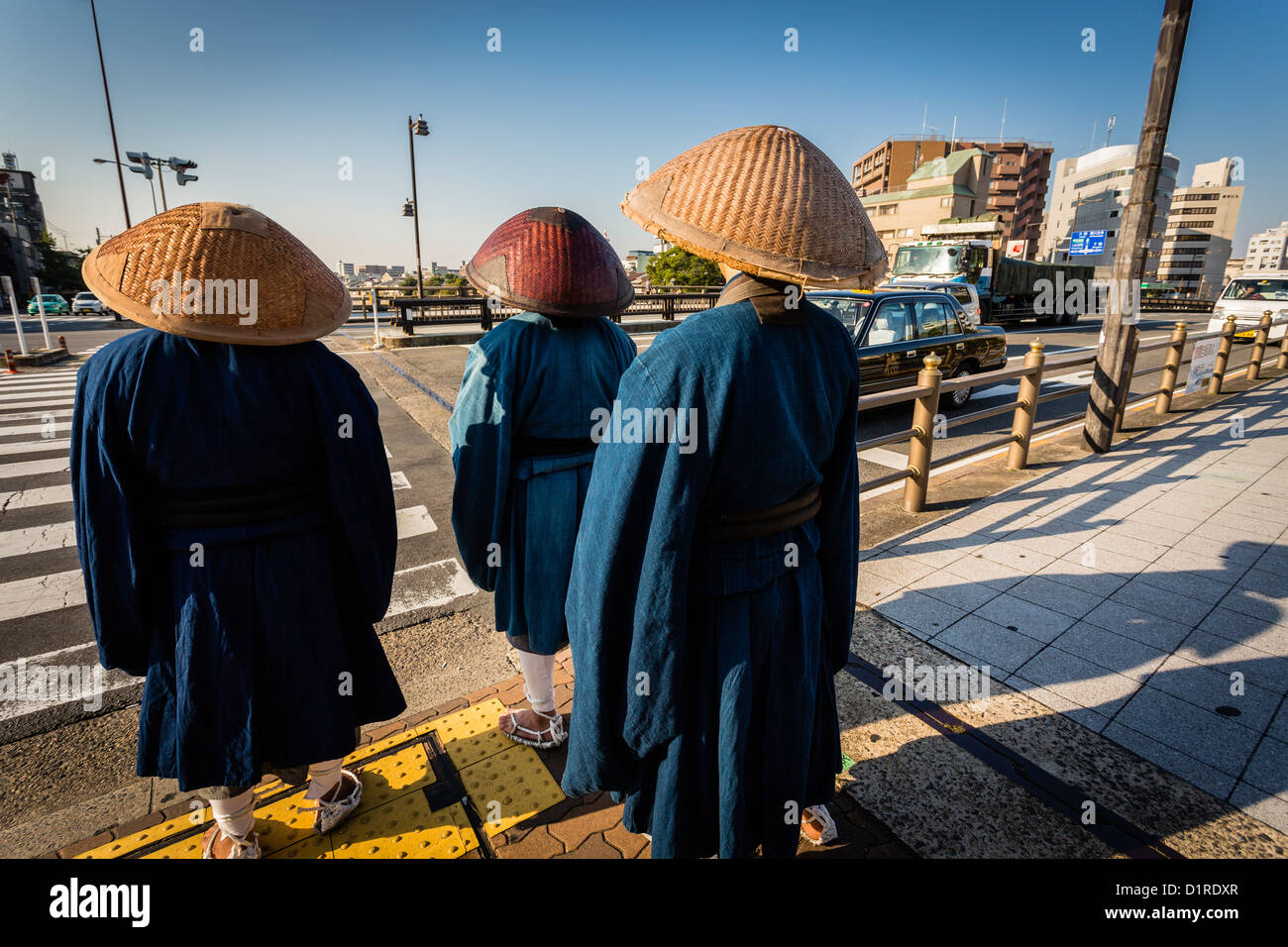 Three men in traditional clothing prepare to cross the street in Kyoto ...