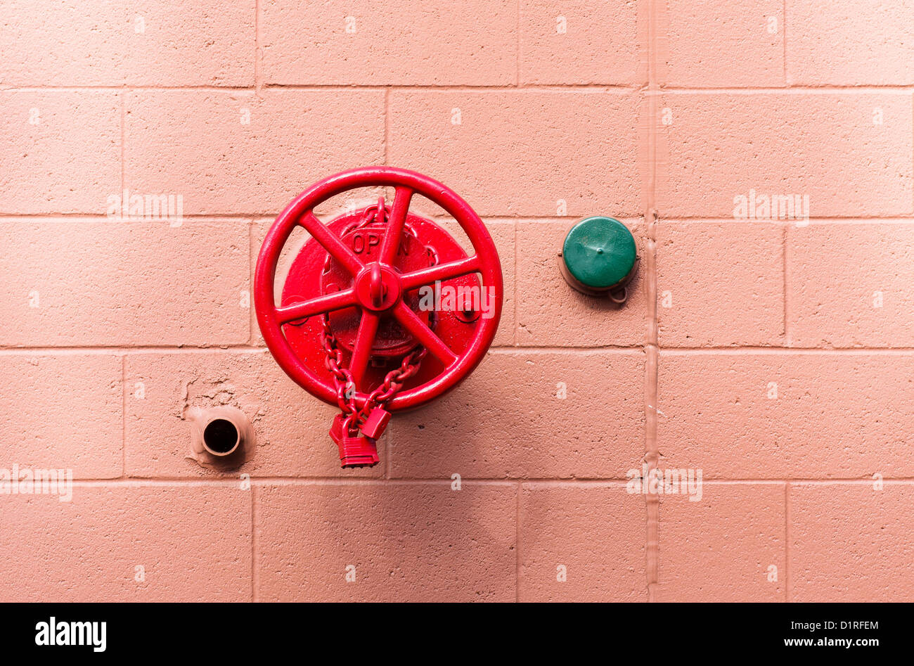 A red fire valve and green pipe cover on a red block wall Stock Photo ...
