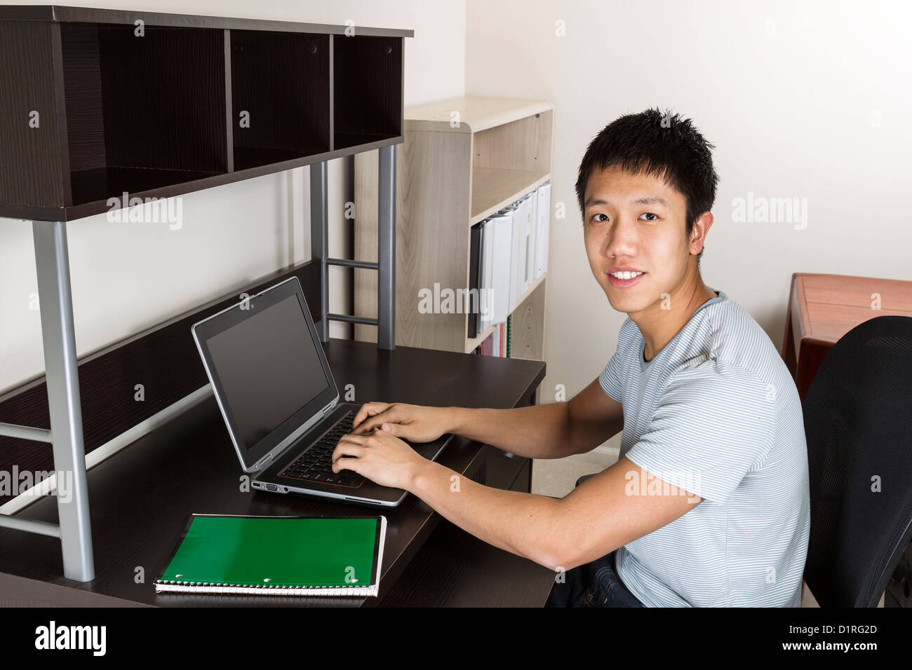 Young man studying at home office for college work with computer and ...