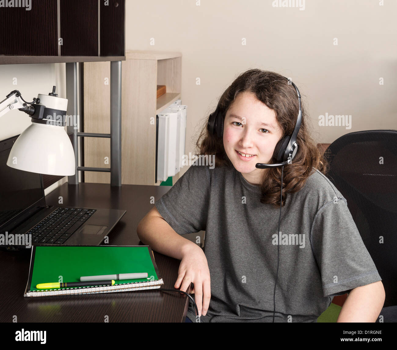 Young girl getting ready to do homework with headset on while sitting ...