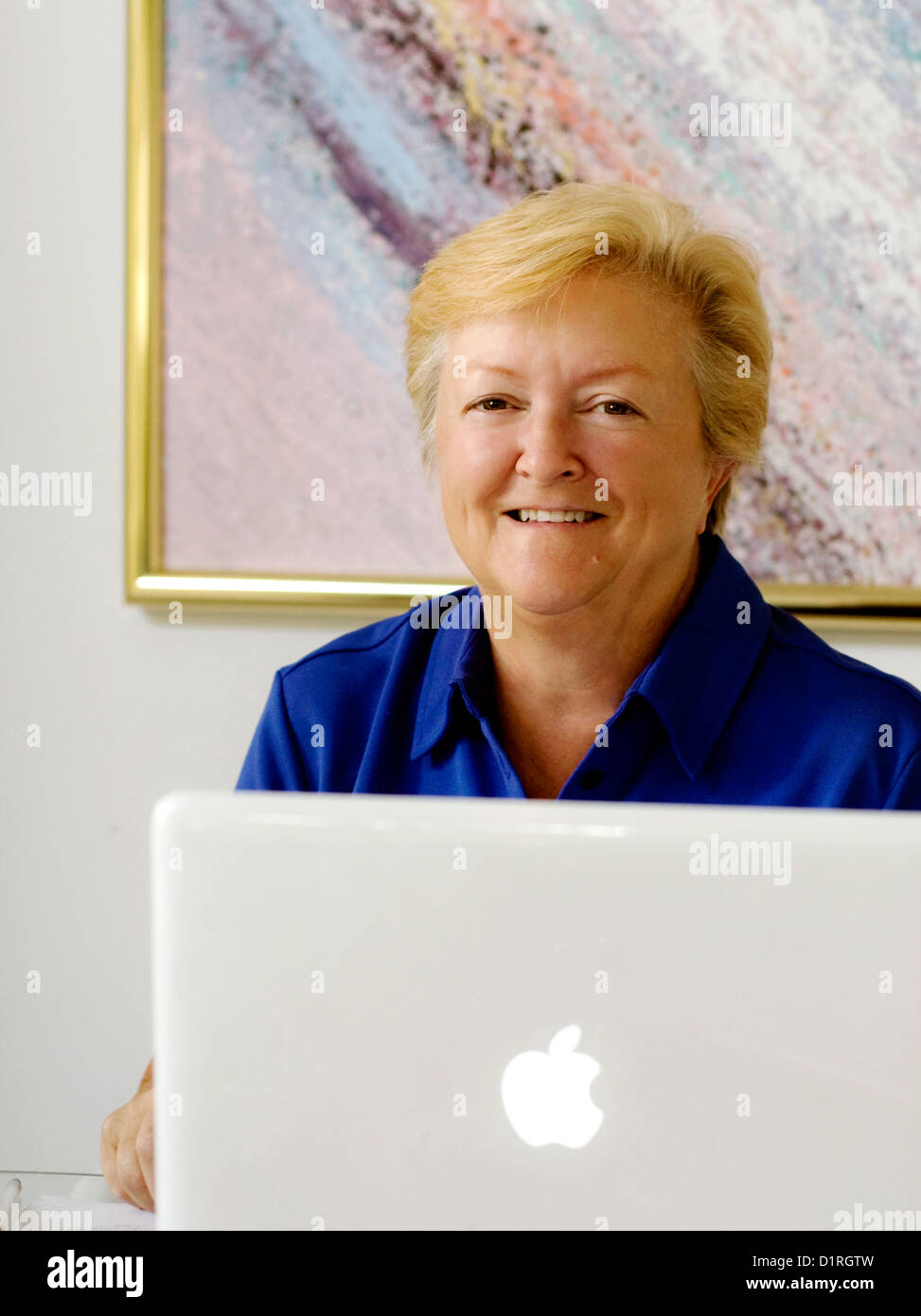 Mature woman smiling behind a laptop computer Stock Photo - Alamy