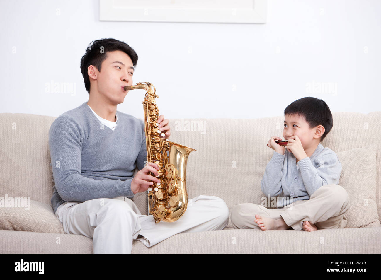 Joyful father and son playing saxophone and harmonica at home Stock Photo - Alamy