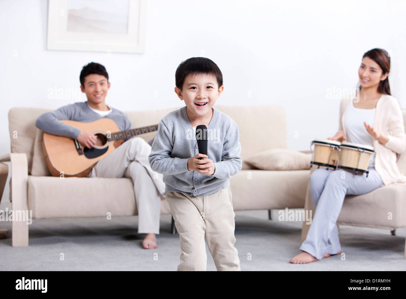 Merry young family playing musical instruments and singing at home ...