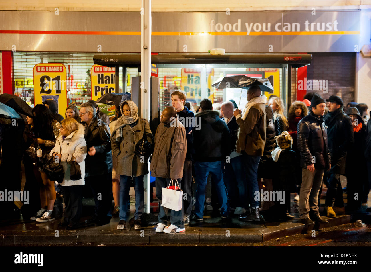 People queue in the rain for buses at Clapham Common in the early hours ...