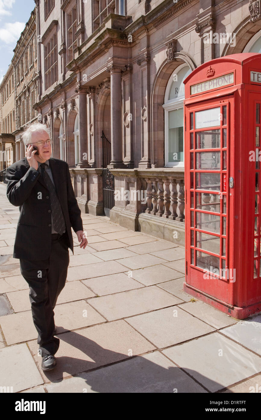 Man walking past a telephone box whilst speaking on mobile phone Stock ...
