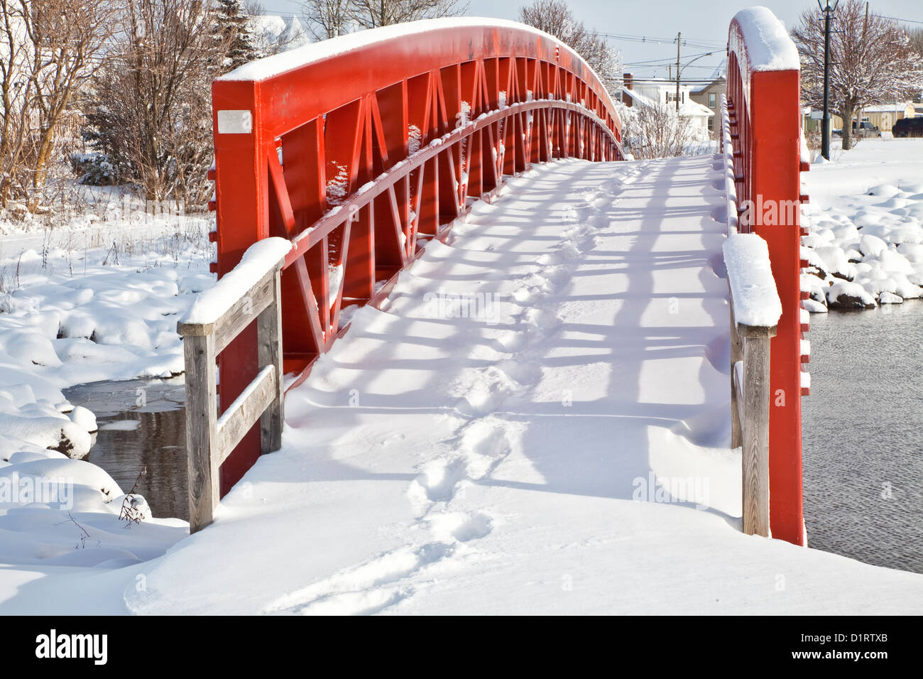 A pedestrian bridge spans a small span of water in the winter landscape ...